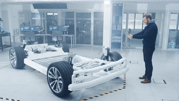 Engineer with Glasses and Beard Scans Electric Car Chassis Prototype ...