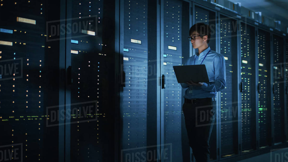 In Dark Data Center: Male IT Specialist Walks along the Row of ...