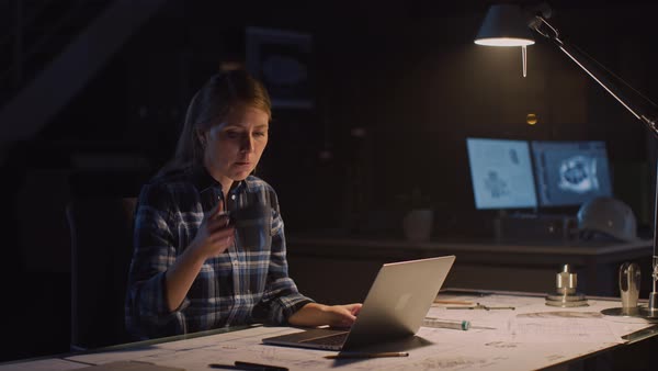 Beautiful female engineer sitting at her desk works on a laptop ...
