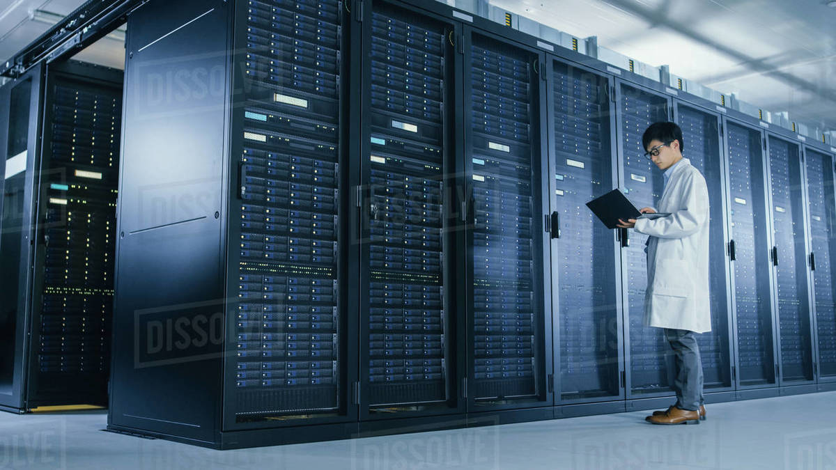 In Data Center: Male IT Specialist Wearing White Coat Stands Beside ...
