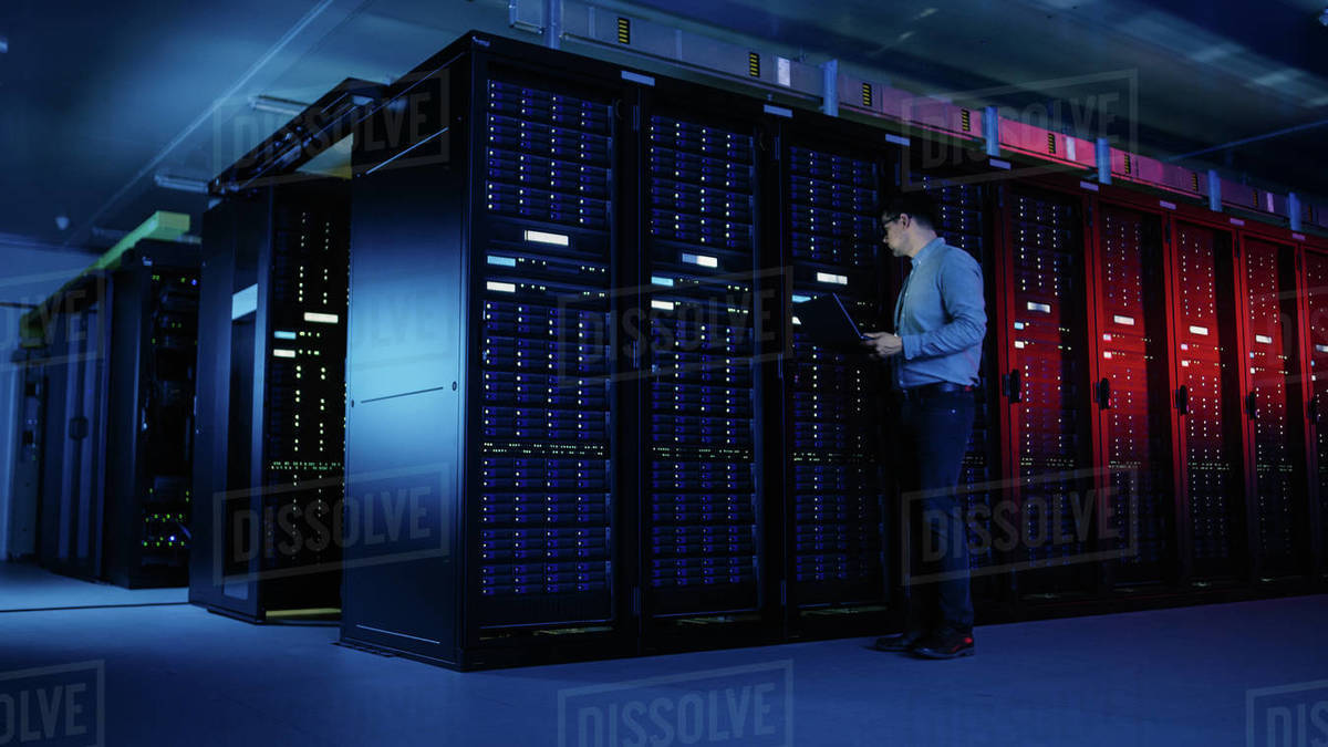 In Data Center: Male IT Specialist Walks along the Row of Operational ...