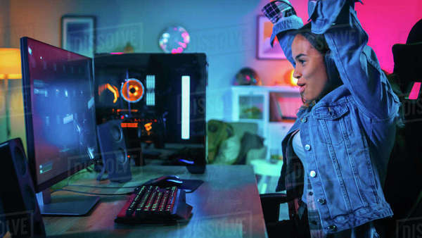 Pretty and excited black gamer girl in headphones is winning in first ...