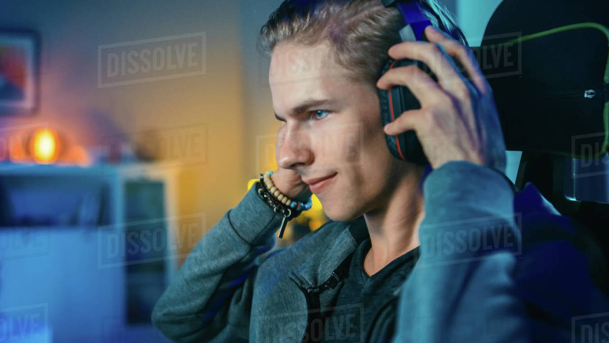 Gamer puts his headset with a mic on and starts playing shooter online ...