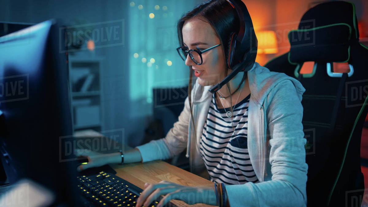 Excited gamer girl in headset with a mic playing online video game on ...