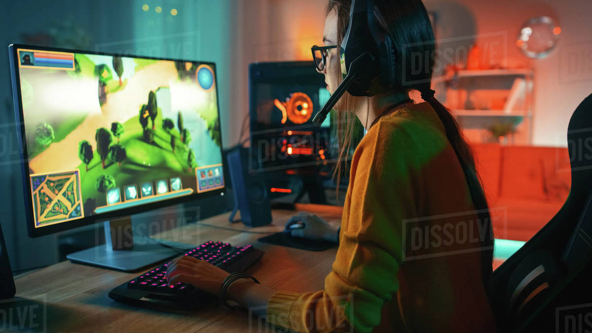 Excited and concentrated gamer girl in glasses and headset with a mic ...