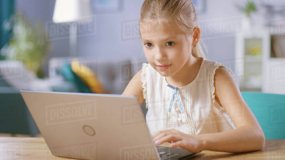 Cute Little Girl Uses Laptop While Sitting at the Desk in the Living ...