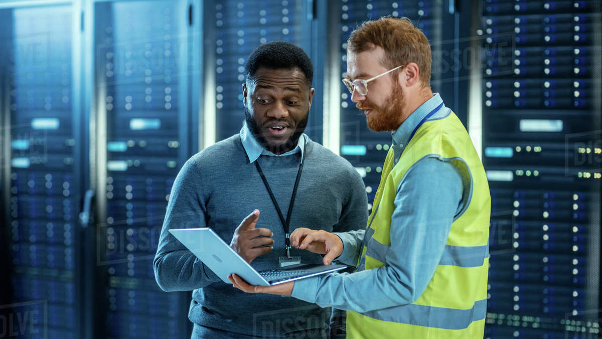 Bearded IT Specialist in Glasses and High Visibility Vest with a Laptop Computer and Black ...