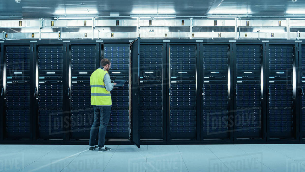 IT Engineer in High Visibility Vest is Working on Laptop in Data Center ...