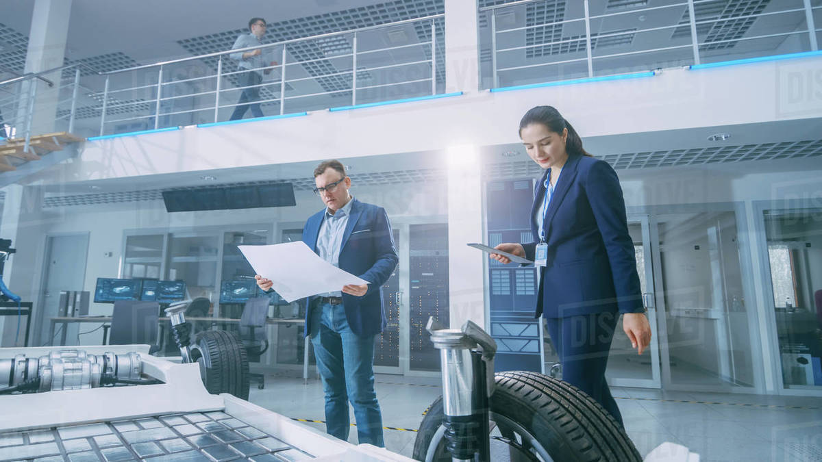 Automotive Design Engineers Looking at Technical Drawings of a Electric ...