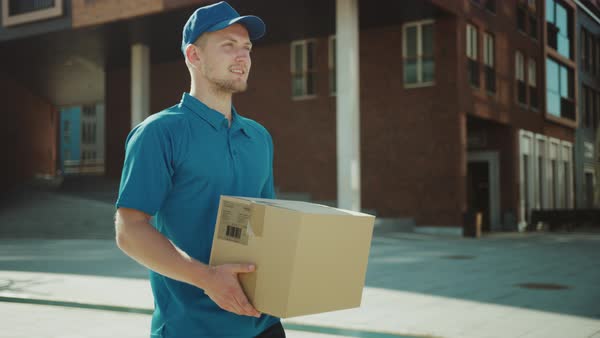 Handsome Delivery Man Holds Cardboard Box Package Walks Through Modern ...