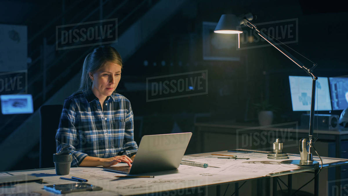 Beautiful Female Engineer Sitting at Her Desk Works on a Laptop ...