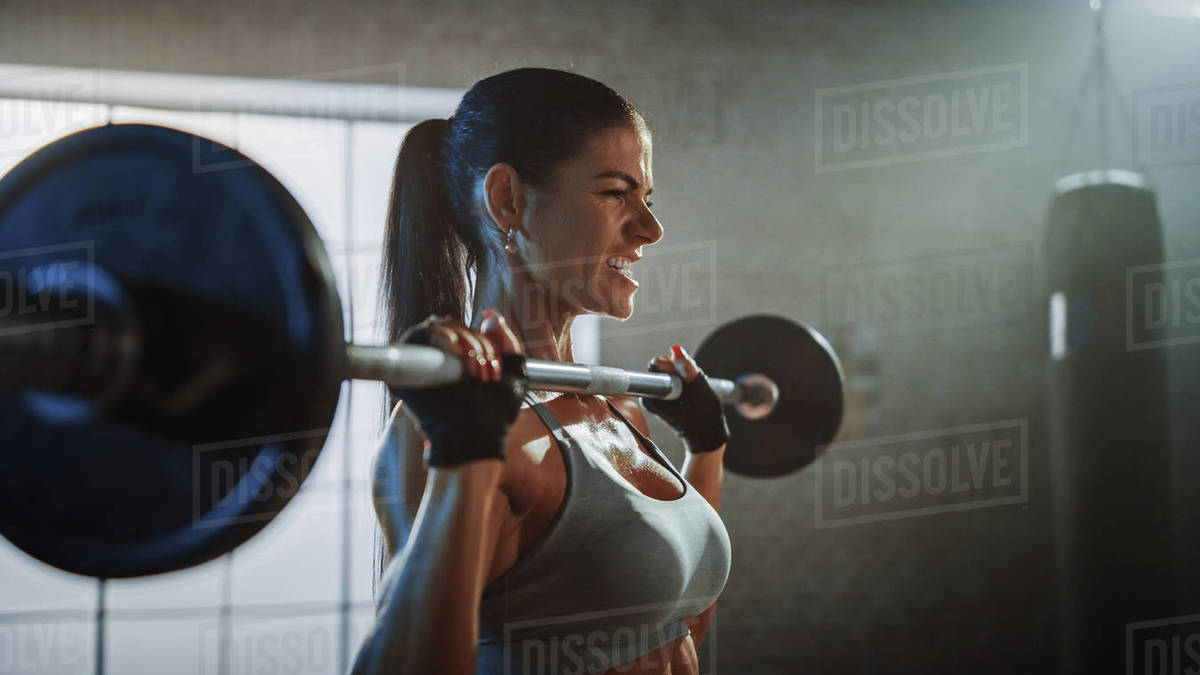 Athletic Beautiful Woman Does Overhead Lift with a Barbell in the Gym ...