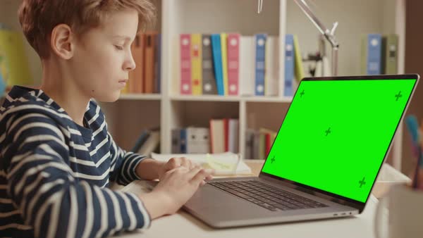 Smart Little Boy Uses Green Screen Laptop for Learning, Writes Down ...