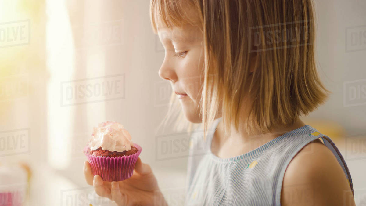In the Kitchen: Adorable Little Girl Eats Creamy Cupcake with Frosting ...
