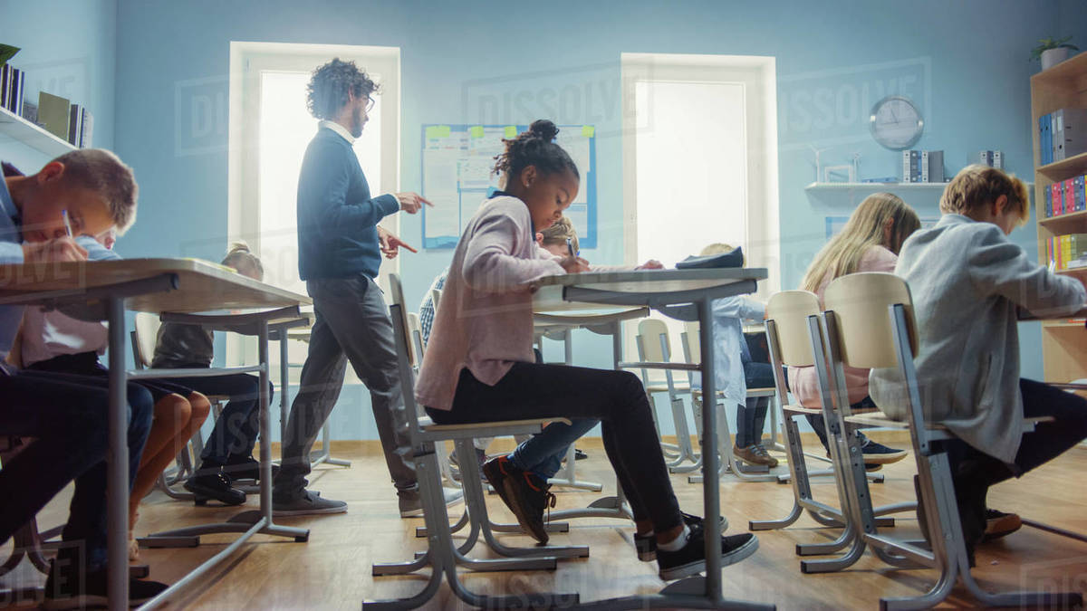 In Elementary School Class: Enthusiastic Teacher walks between Rows of ...
