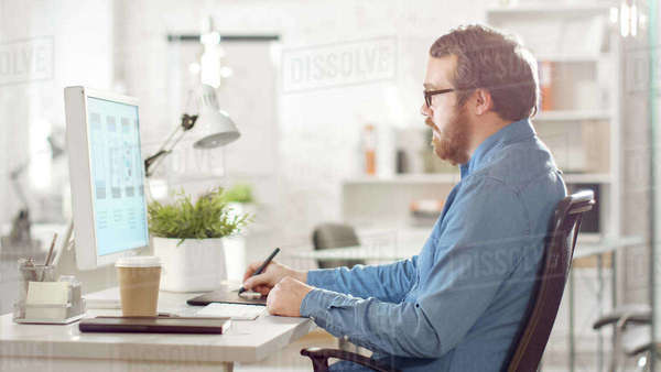 Young Bearded Man Working on His Personal Computer and Taking Notes ...