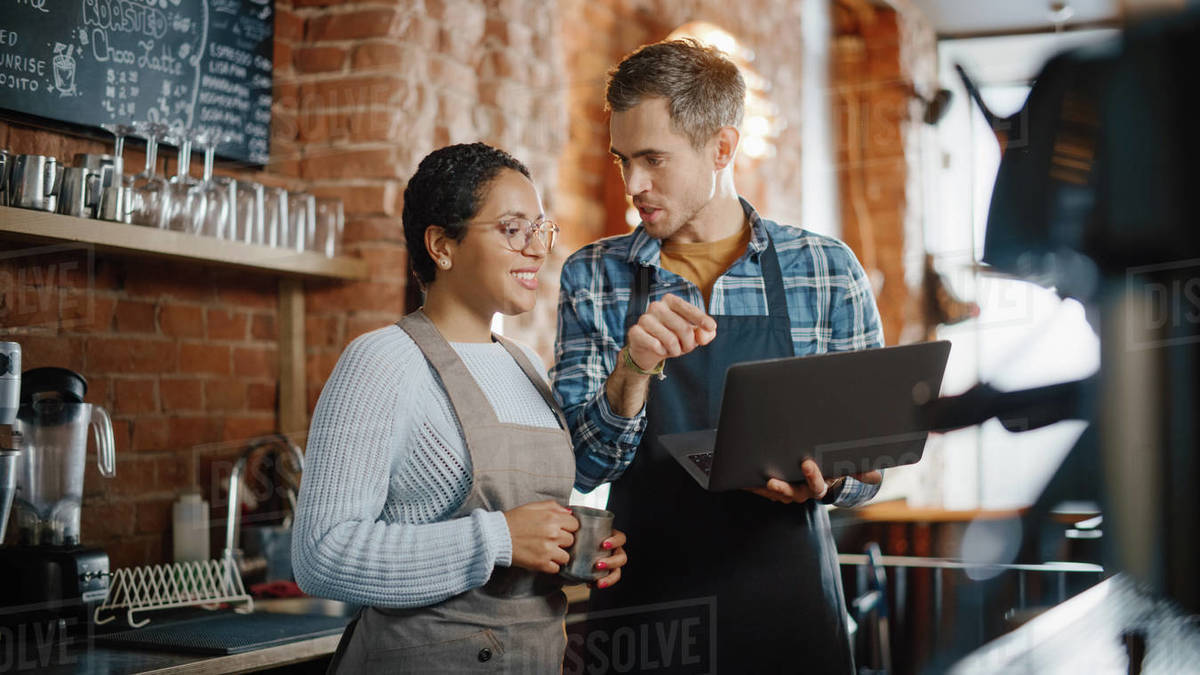 Two barista's having a team meeting and going over notes while working ...