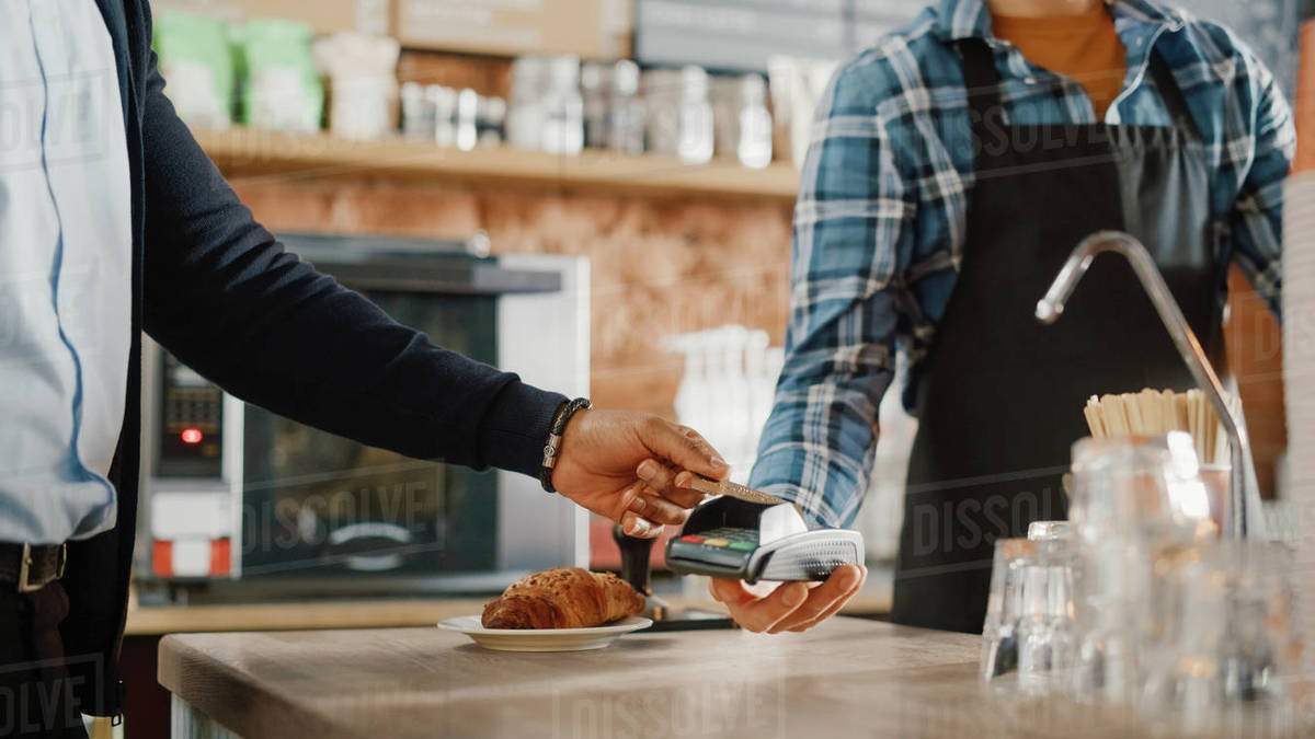 Close-up view of barista handing payment terminal to customer using a ...