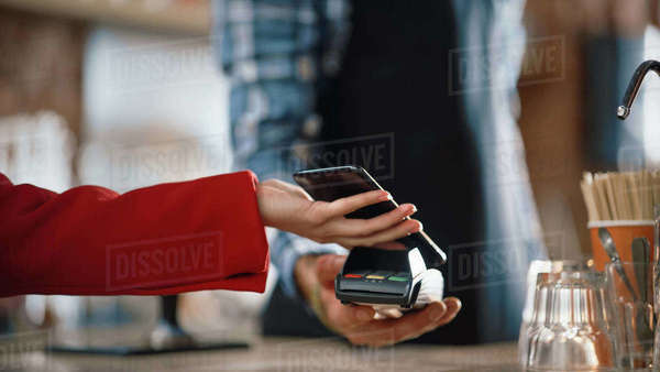 Close-up view of barista handing payment terminal to customer using ...