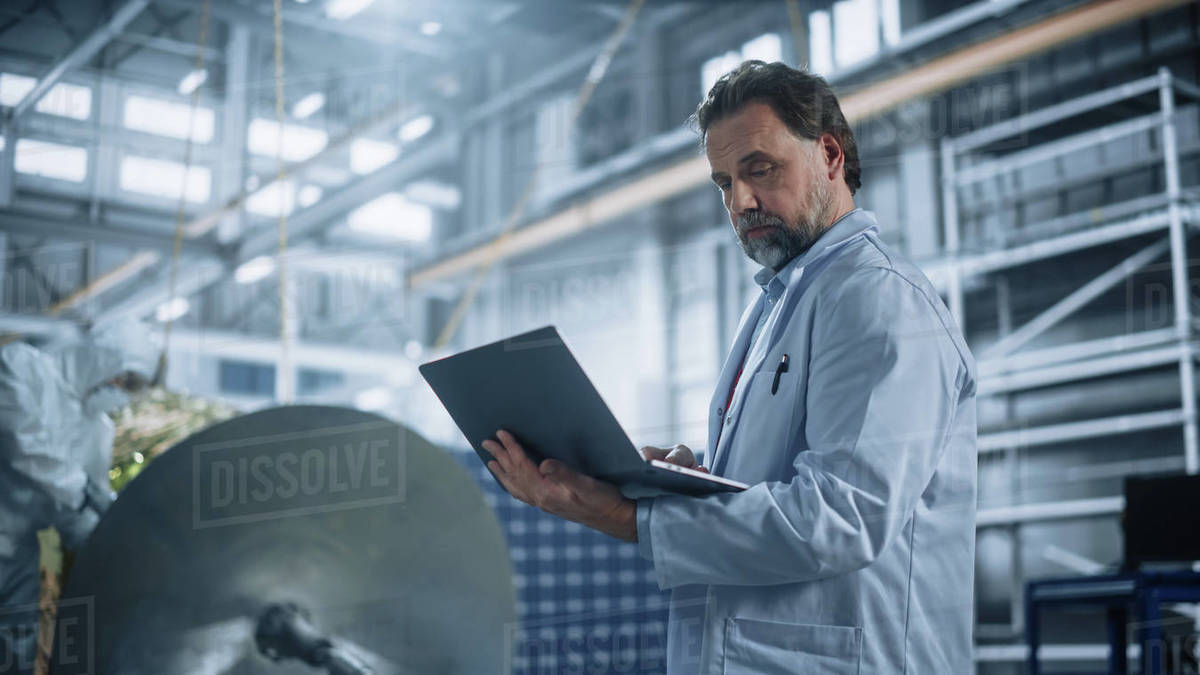Male Engineer Uses Laptop Computer while Working on Satellite ...