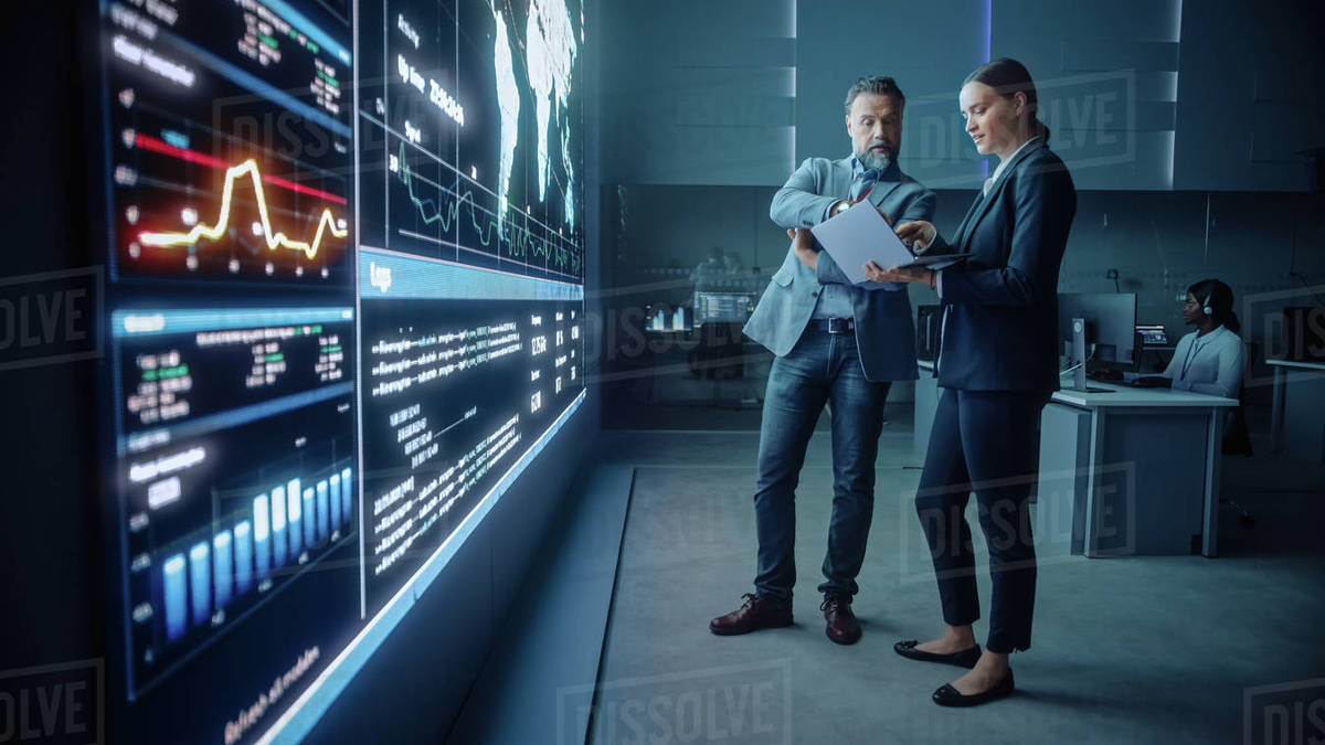 Project Manager and Computer Science Engineer Talk while Using Big Screen Display and a Laptop ...