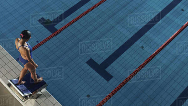 Female Swimmer Stands on a Starting Block, ready to Jump into Swimming ...