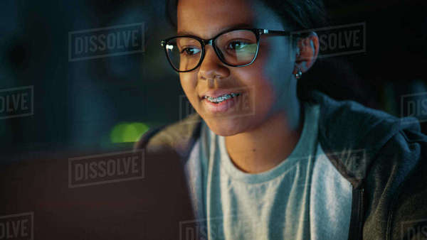 Young Teenage Black Girl Using Laptop Computer in a Dark Cozy Room at ...
