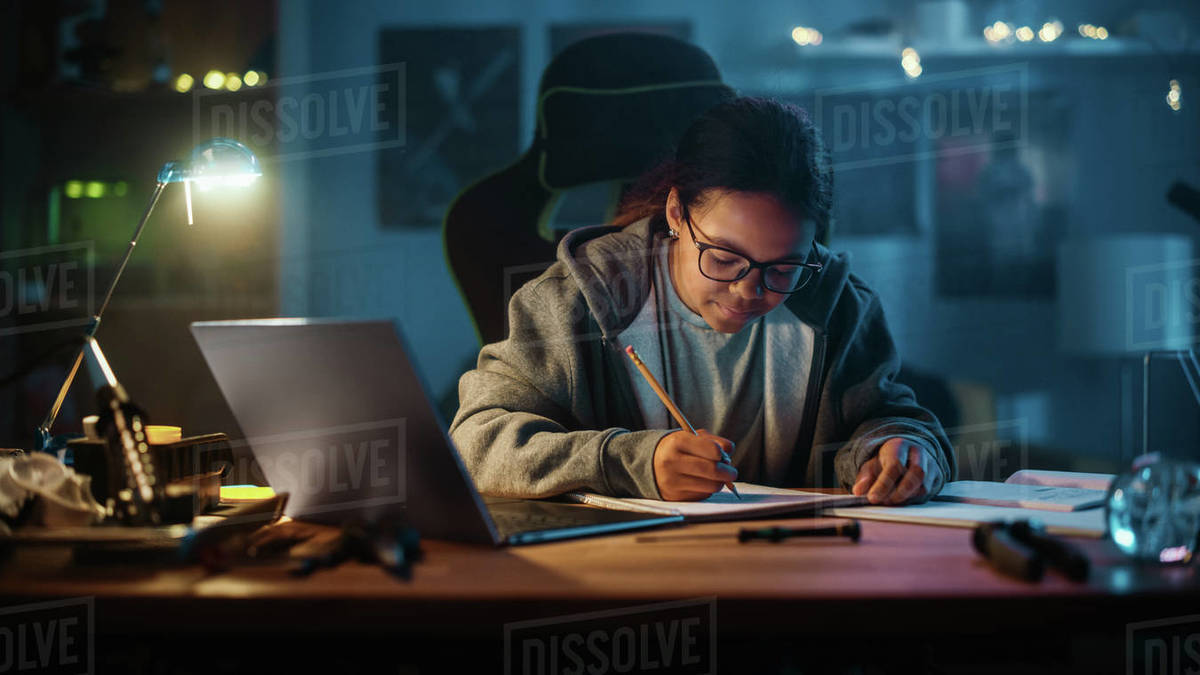 Young Teenage Black Girl Writing Down Homework in a Notebook with a ...