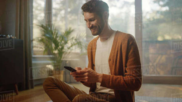 Man Using Smartphone at Home - Stock Photo - Dissolve