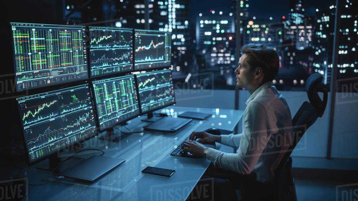 Financial Analyst Working on a Computer with Multi-Monitor Workstation with Real-Time Stocks ...