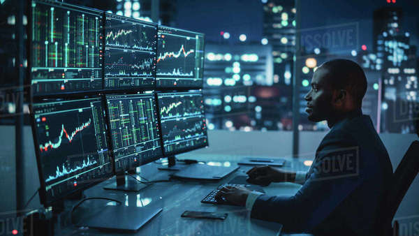 Financial Analyst Working on Computer with Multi-Monitor Workstation ...