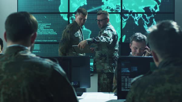 Group of military IT professionals on briefing in monitoring room ...
