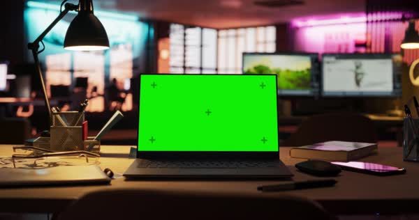 Zoom in Shot of Laptop Computer Standing on a Wooden Desk with a Green ...
