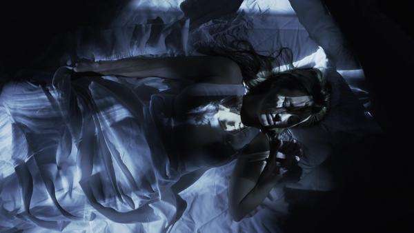 High angle medium shot of nightmare projections on sleeping woman ...