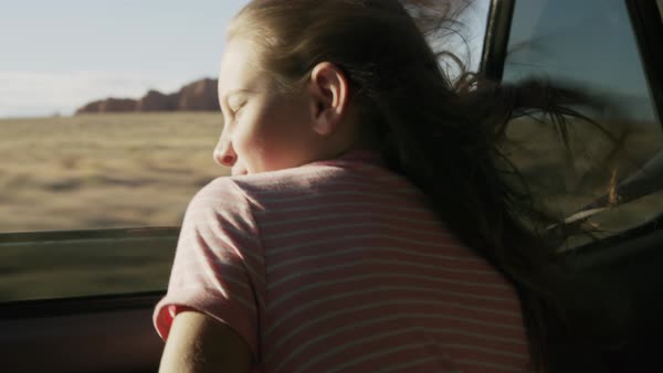 Girl in car leaning out car window enjoying wind blowing hair - Stock ...