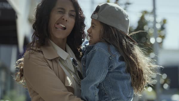 Close up of portrait of silly mother and daughter making faces in city ...