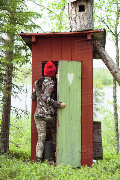 Woman entering wooden outhouse - Royalty-free Stock Photo | Dissolve