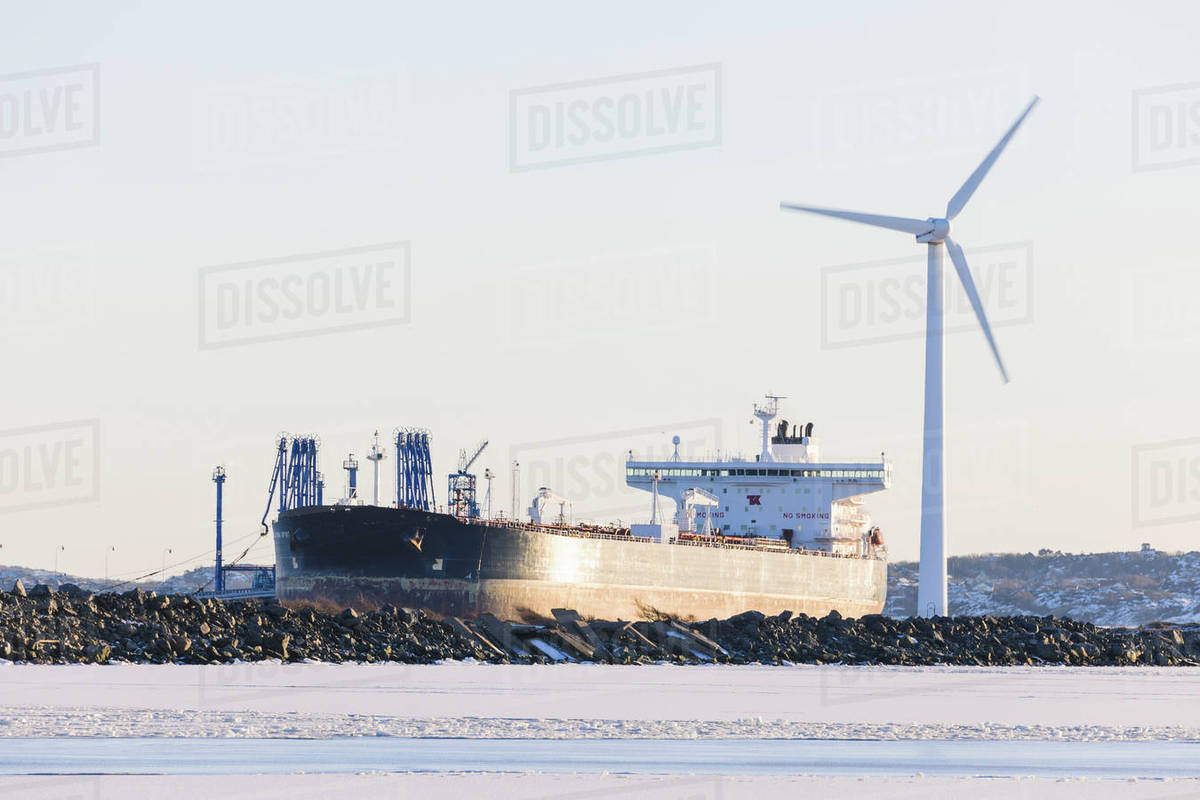 Wind turbine at coast, cargo ship on background - Stock Photo - Dissolve