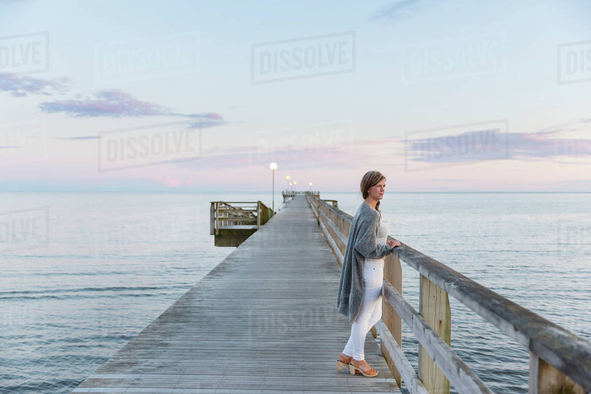 Woman on pier looking at sea - Royalty-free Stock Photo | Dissolve