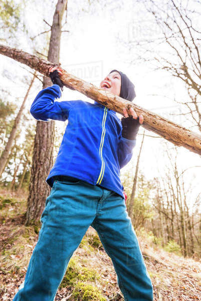 Boy carry tree trunk - Stock Photo - Dissolve