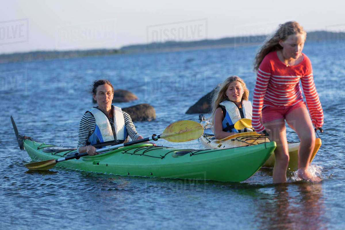 Girl pulling kayaks in sea - Royalty-free Stock Photo | Dissolve