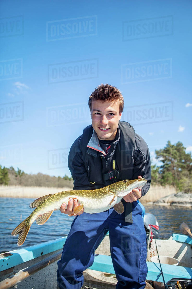Young man holding caught fish - Stock Photo - Dissolve