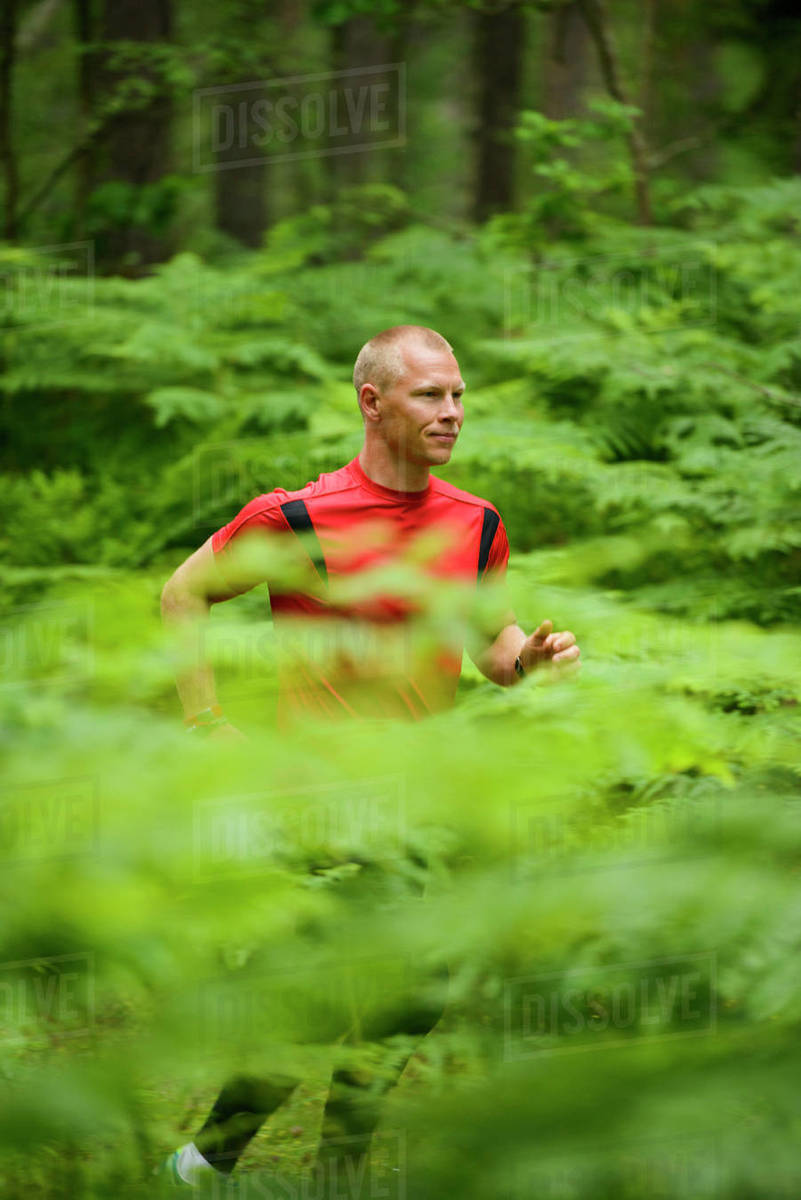 Young man running through forest - Royalty-free Stock Photo | Dissolve