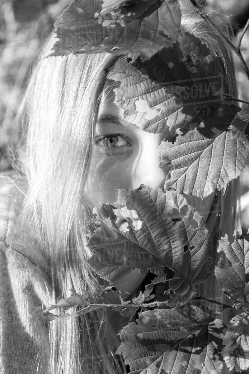 Blond girl hiding behind tree branch - Royalty-free Stock Photo | Dissolve