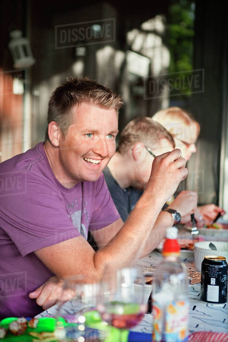 Smiling man sitting at dinner table - Stock Photo - Dissolve
