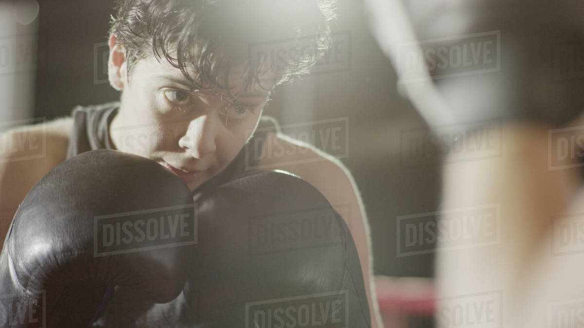 Close up of female boxer protecting her face standing in boxing ring ...