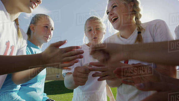 Low angle blurred view of soccer team players cheering in huddle before ...