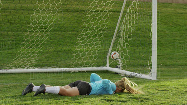 Goalie protecting goal and laying on soccer field during game - Royalty ...