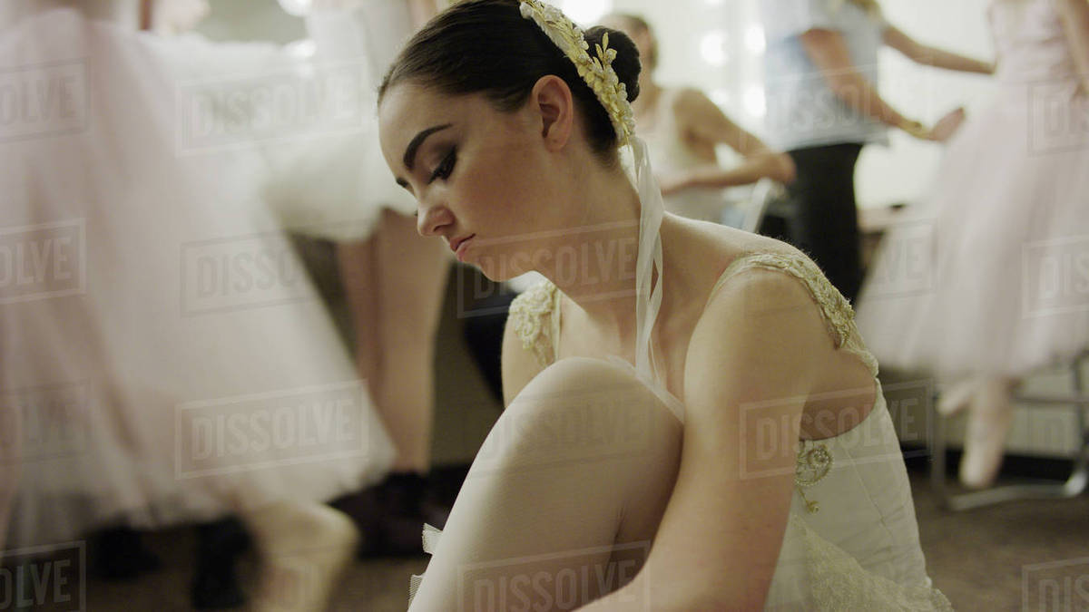 Serious ballet dancer in costume stretching backstage before show ...
