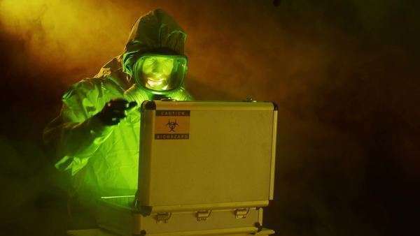 A man dressed in military grade hazmat suit places a biohazard sample ...
